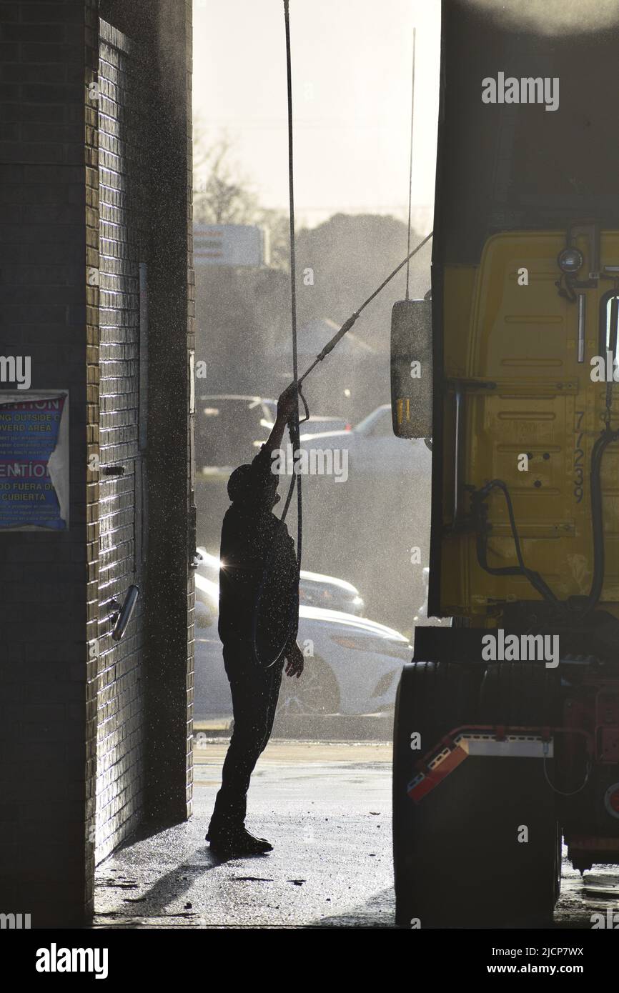 Man washing a semi-truck cab in the early morning at a truck wash in ...