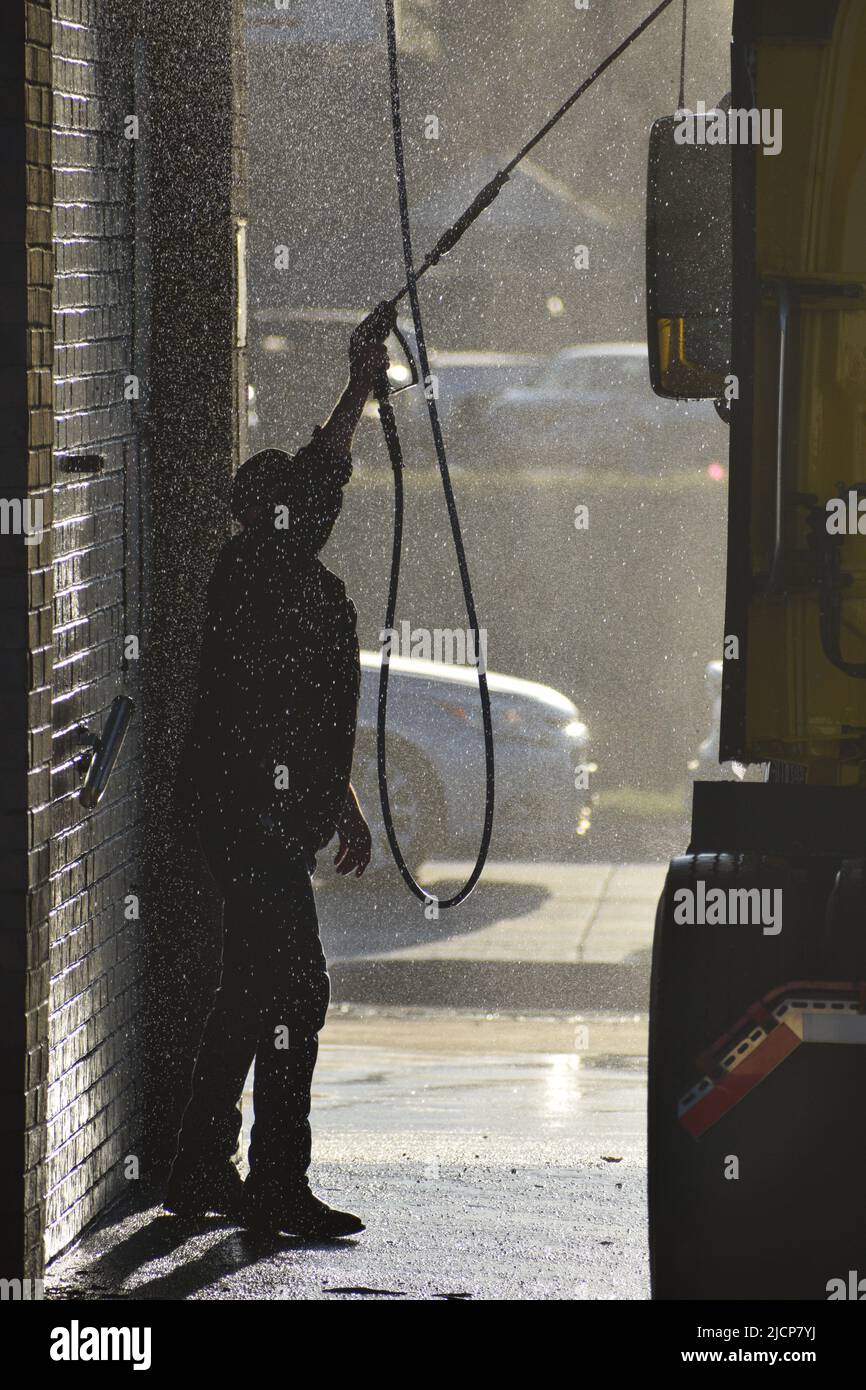 Man washing a semi-truck cab in the early morning at a truck wash in ...