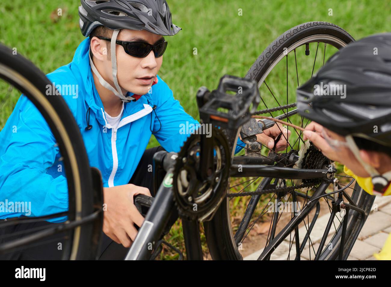 Serious man in helmet and sunglasses checking if bicycle wheel is ...