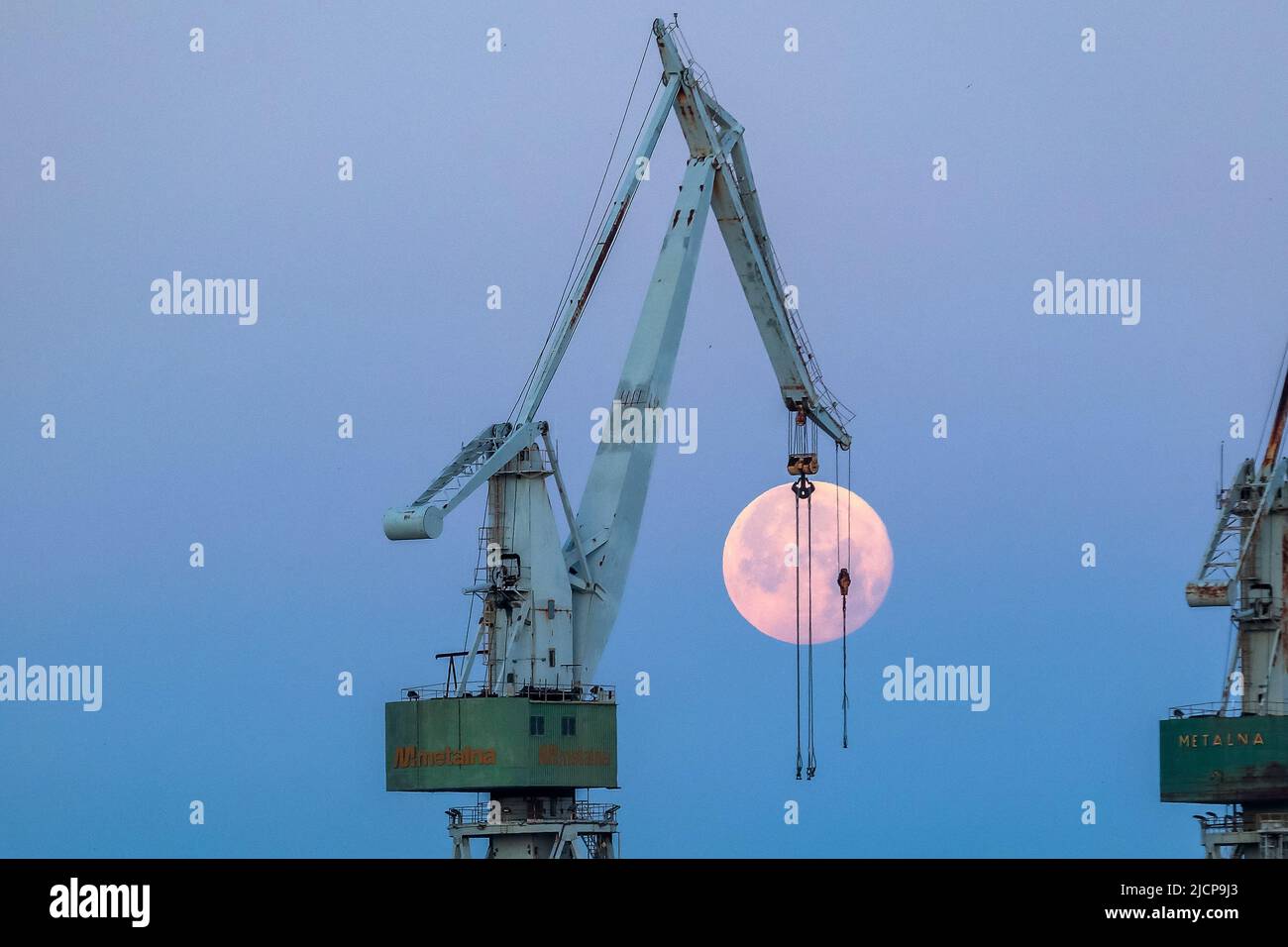 Strawberry Full Moon sets behind cranes at Uljanik Shipyard, in Pula ...