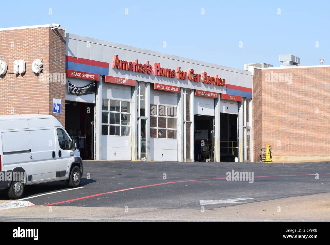 Open garage doors at a Firestone auto repair shop; white van parked on ...