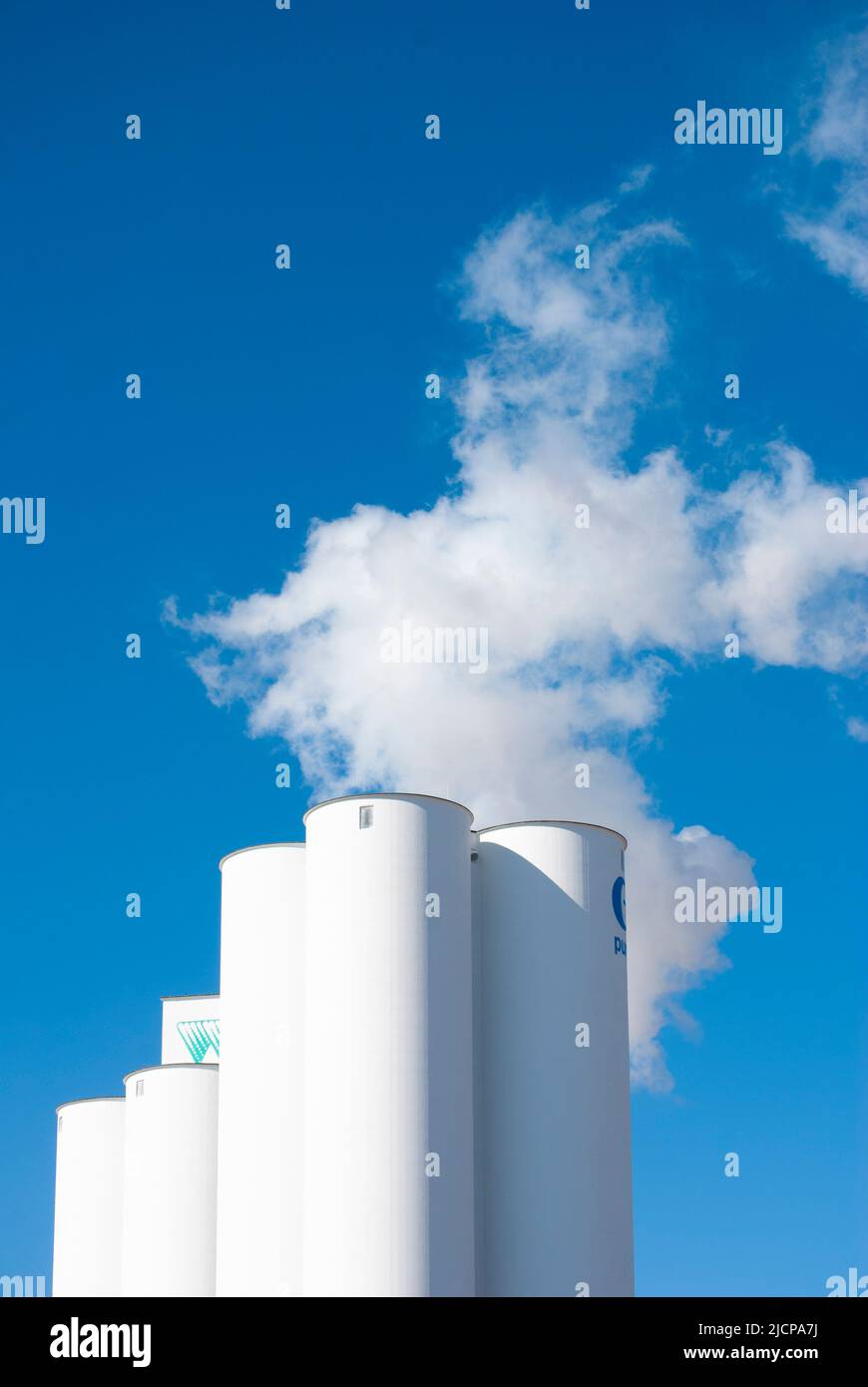 White smoke or steam coming from a smokestack and a bright blue sky ...