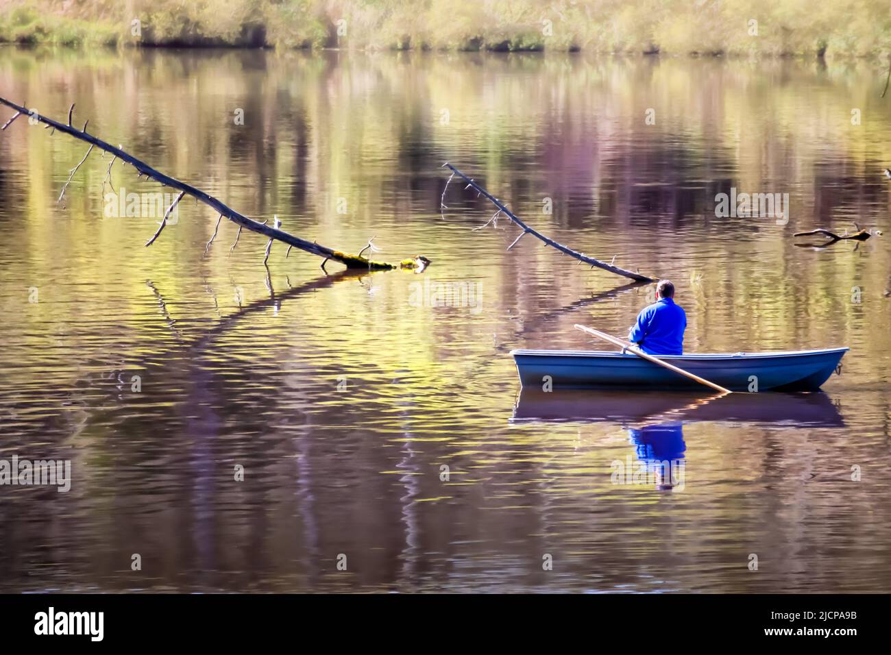 Man wearing red jacket sitting on a round shape boat around a lake ...