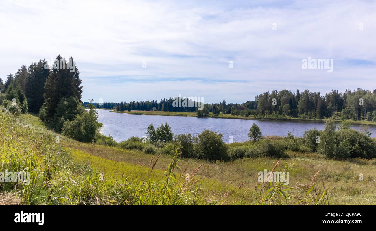 Nature photo with a light blue lake, green trees and summer sunshine ...