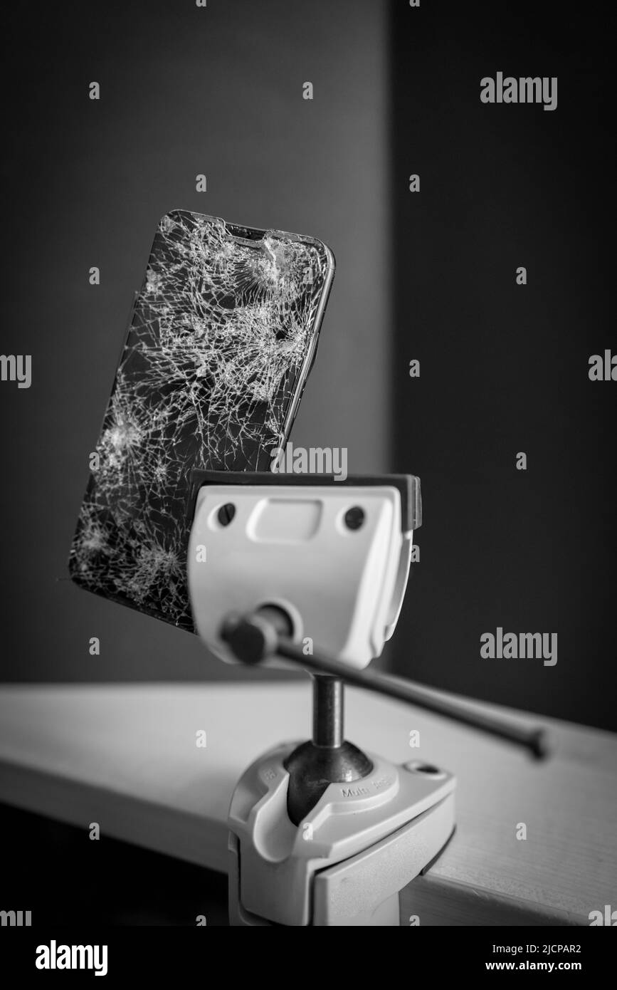 a completely destroyed cell phone is clamped in a vice Stock Photo - Alamy