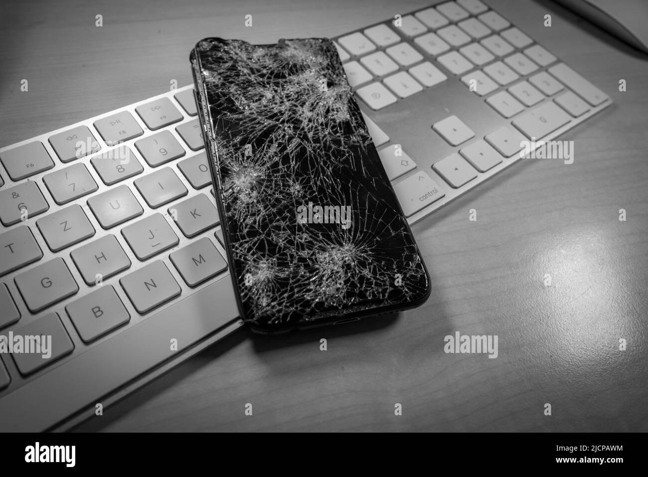 a completely destroyed cell phone lies on a computer keyboard Stock ...