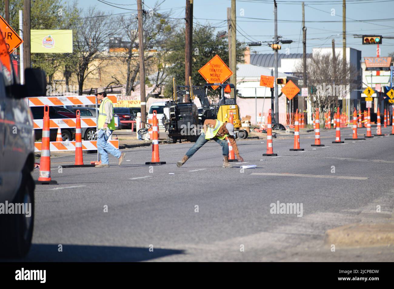 Road construction workers walking across a street in a construction ...