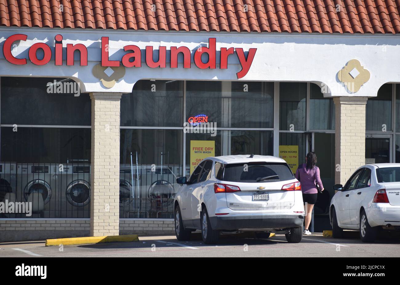 Hispanic woman walking into a coin operated laundromat Stock Photo - Alamy