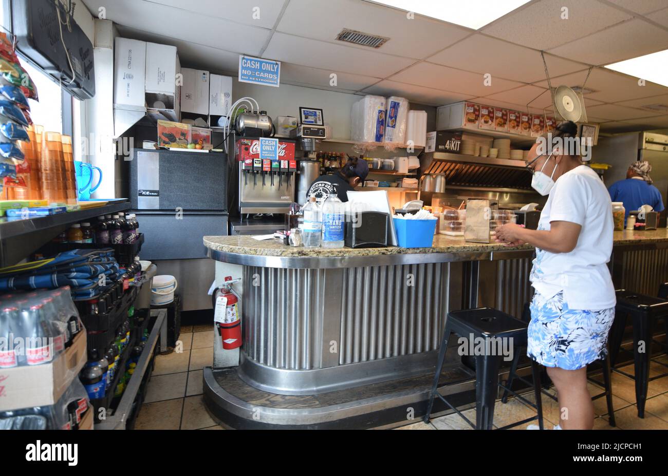 A hungry customer, wearing a mask, waits for her food at the Record ...