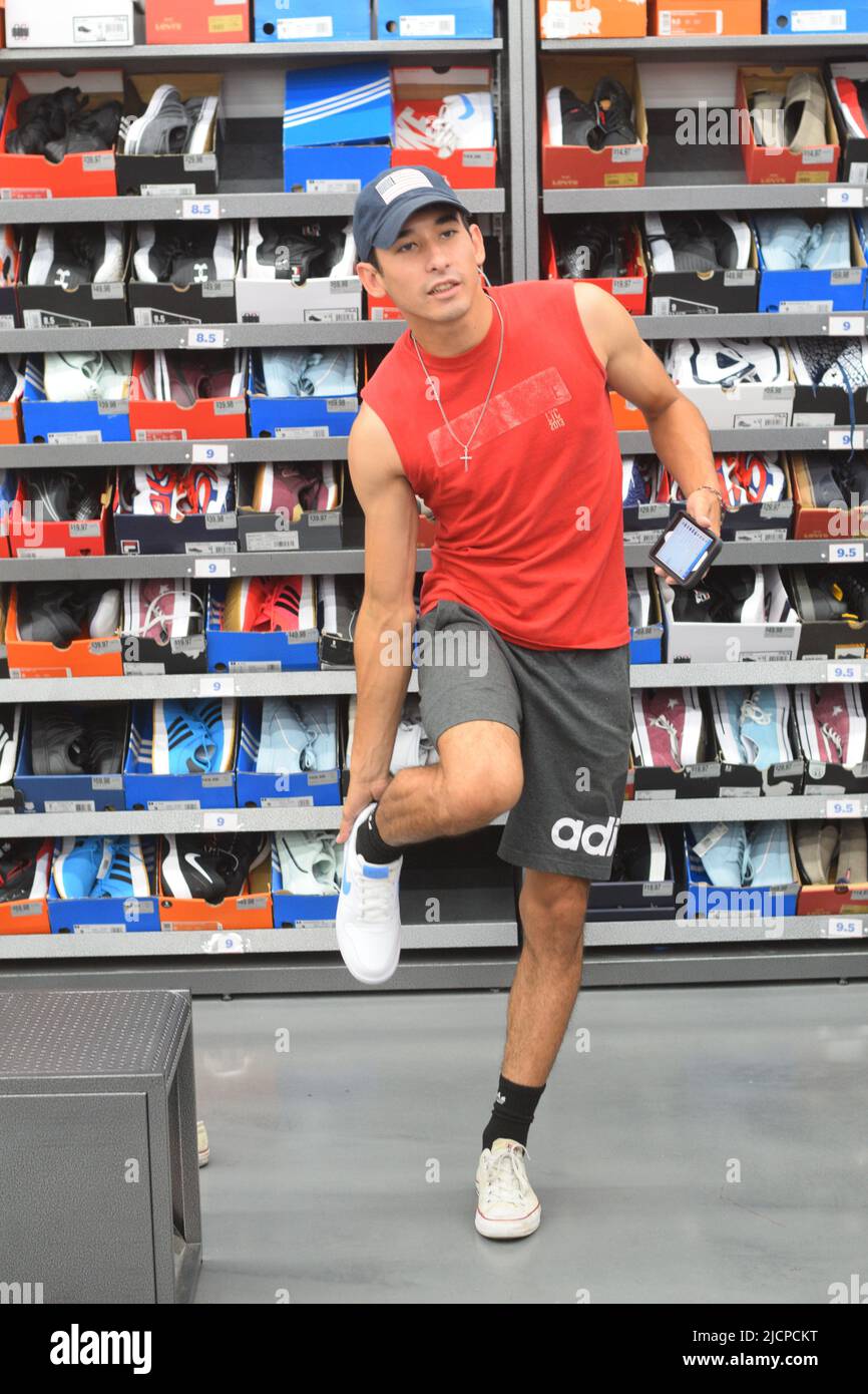 Generation Z (Gen Z) young man inside a shoe store, trying on shoes ...