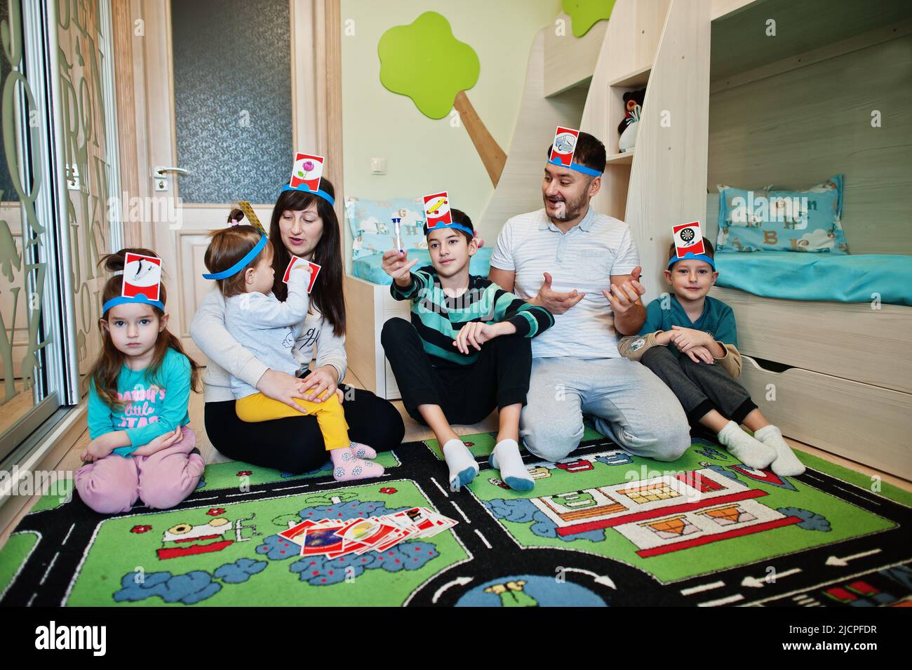 Happy family with four kids playing game guess who while having fun at ...