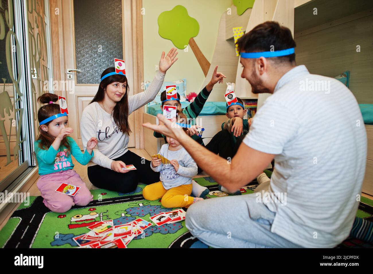 Happy family with four kids playing game guess who while having fun at ...