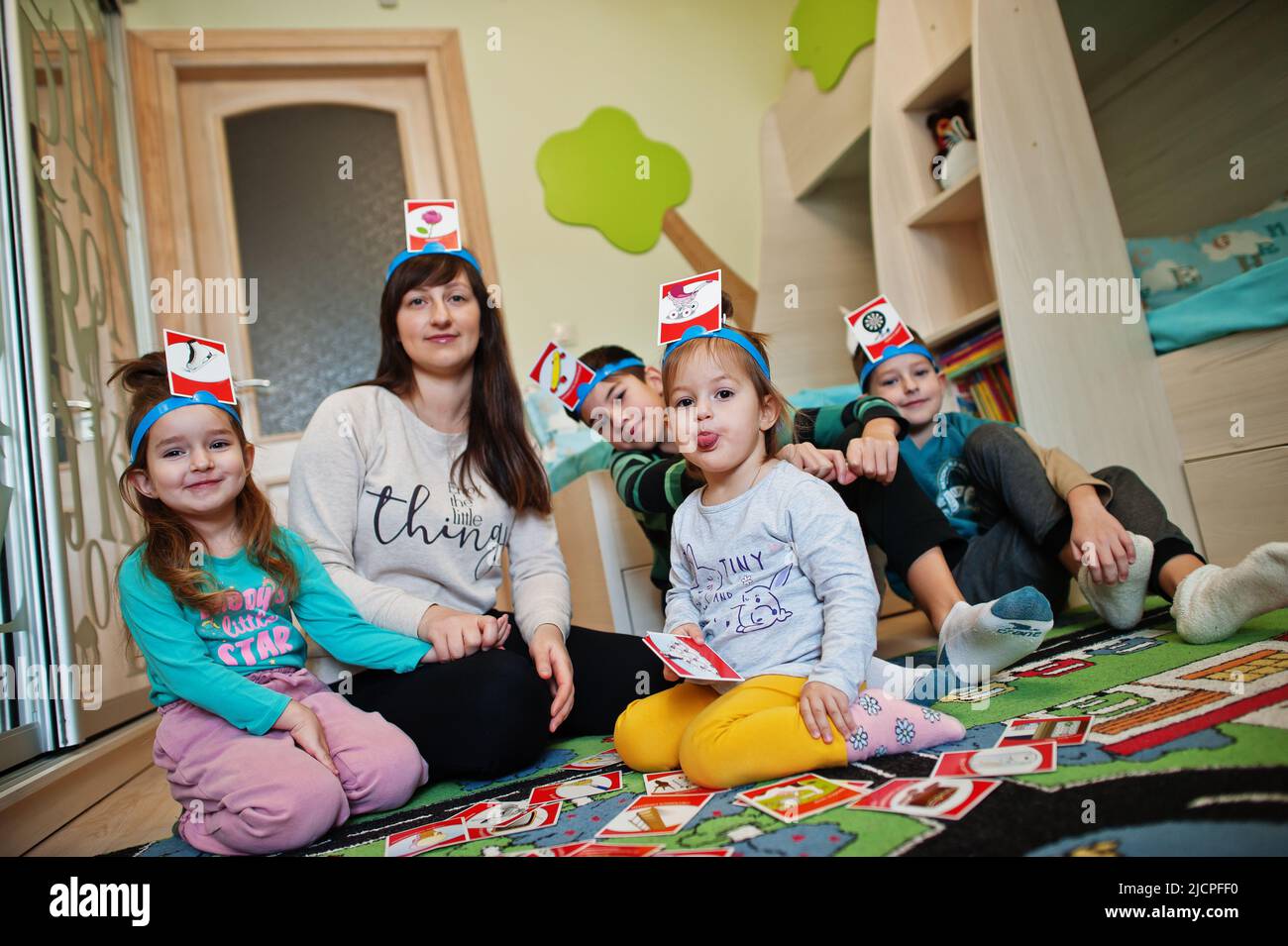 Happy family with four kids playing game guess who while having fun at ...