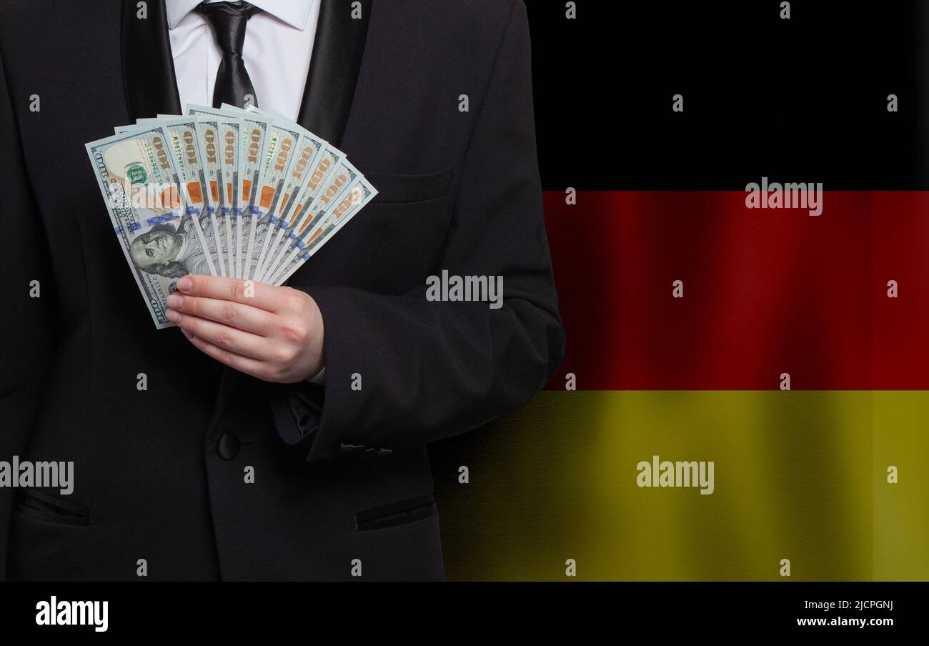 German business man hand holding US 100 dollar bills against flag of ...
