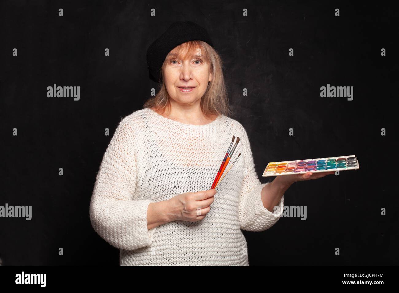 Happy middle aged senior woman artist with colorful paints against ...