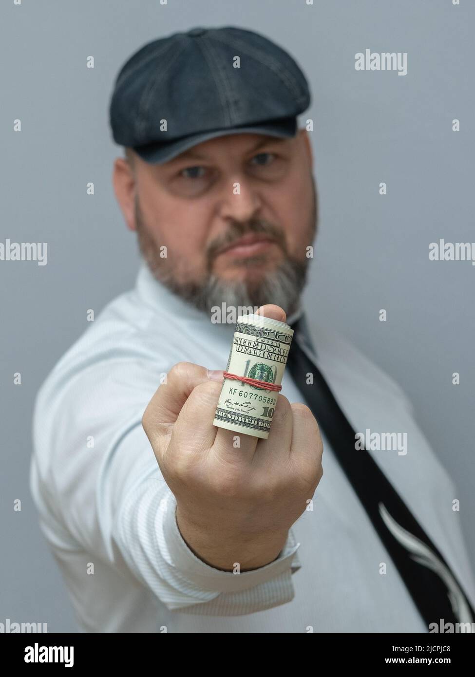 A man shows the middle finger on which dollars are rolled up into a ...