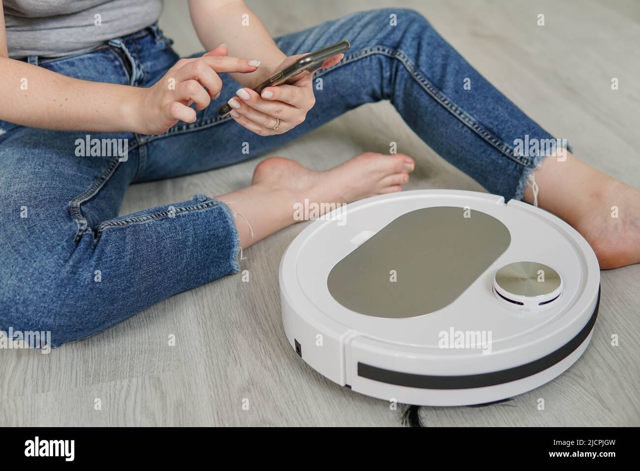 Woman housewife using mobile application to control robotic vacuum ...