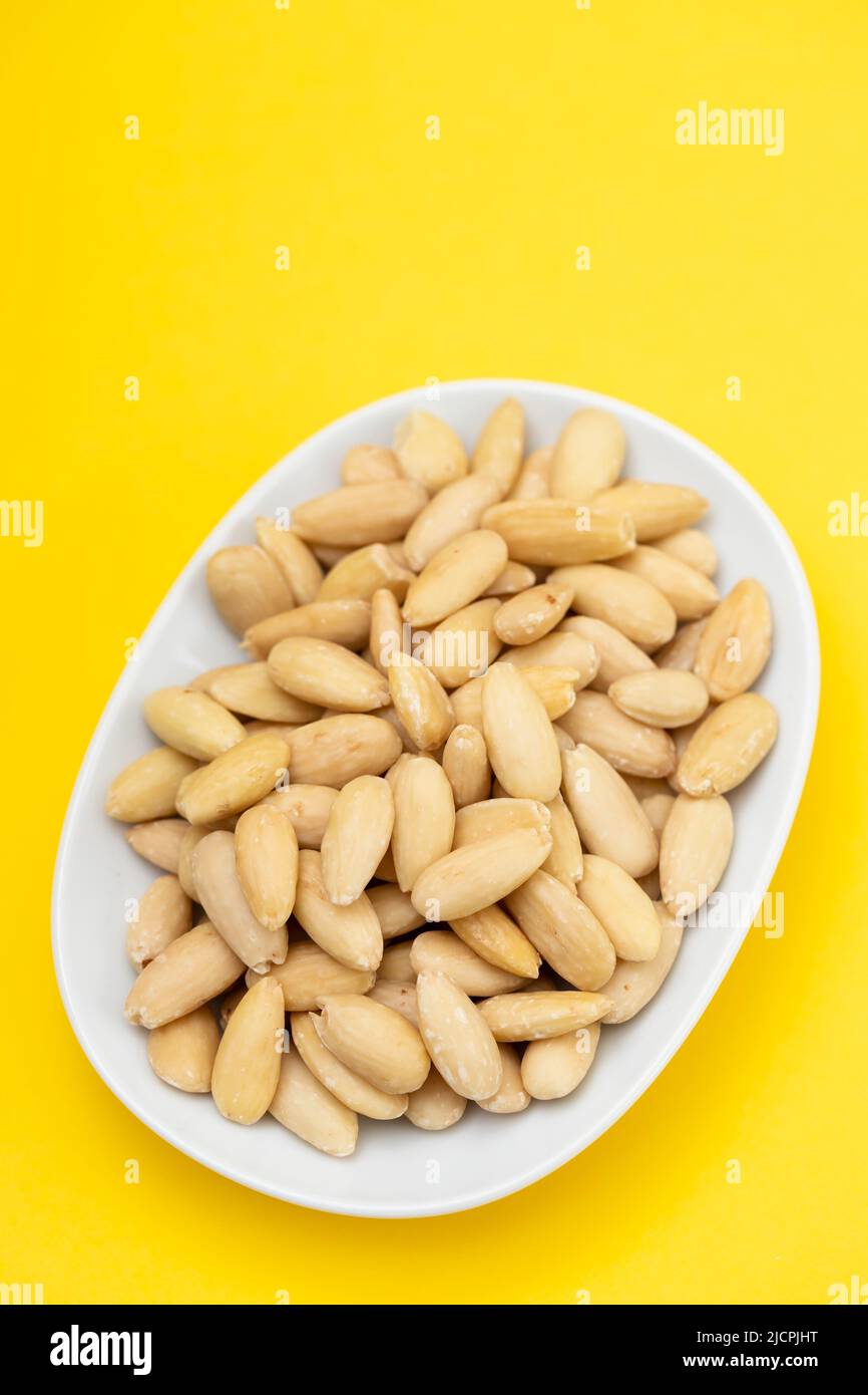 clean almonds on small white dish on yellow paper Stock Photo - Alamy