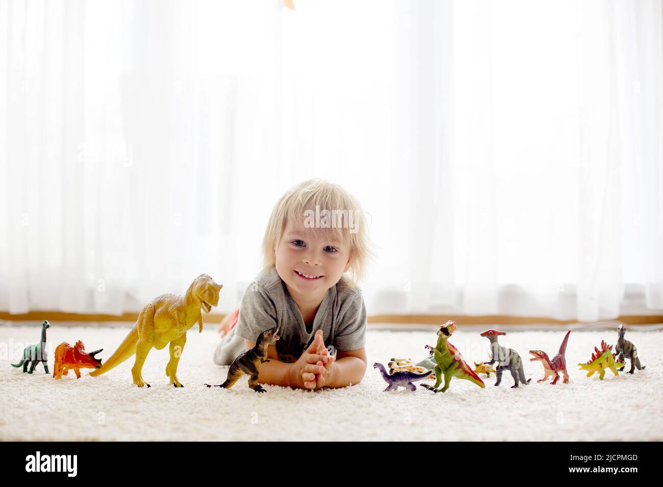 Blond toddler child, playing with dinosaurs at home, nice soft back ...