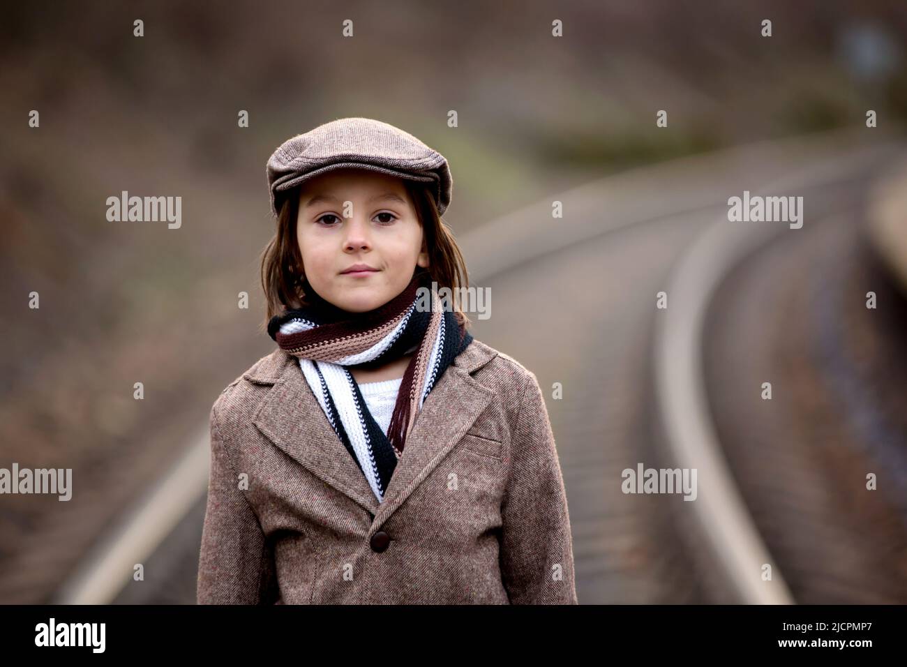 Adorable boy on a railway station, waiting for the train, running and ...