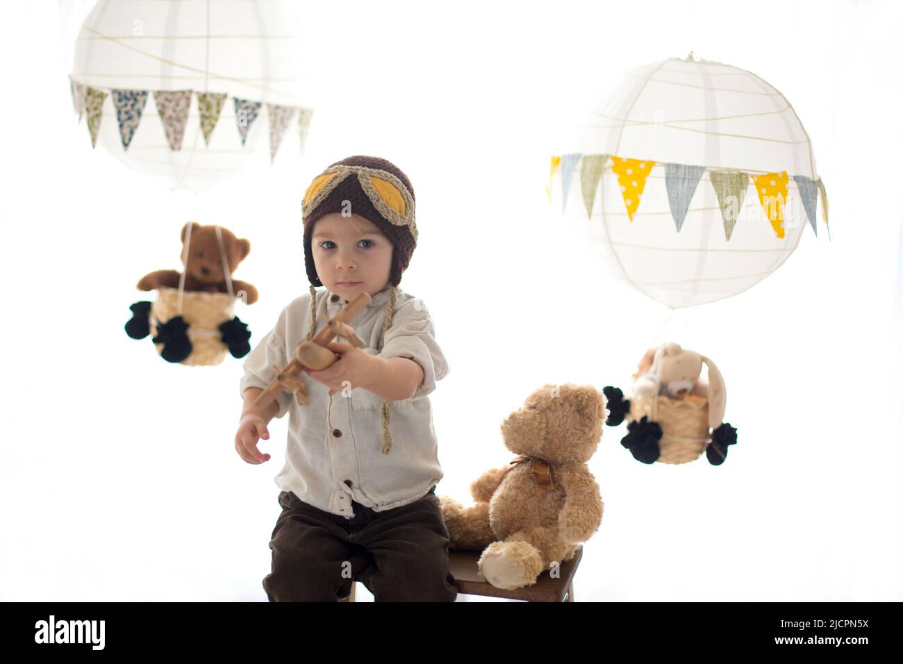 Sweet toddler boy, playing with airplane and teddy bear, decorated air ...