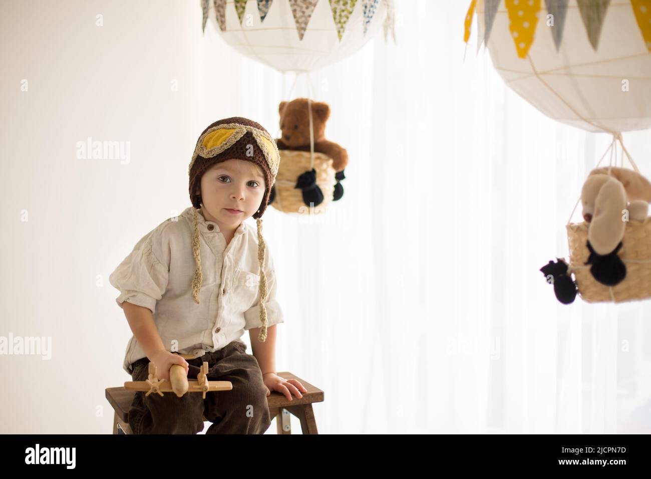 Sweet toddler boy, playing with airplane and teddy bear, decorated air ...
