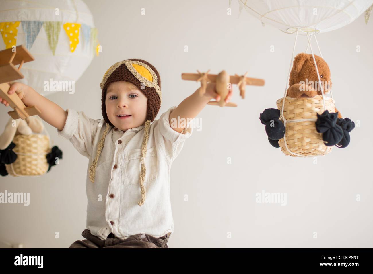 Sweet toddler boy, playing with airplane and teddy bear, decorated air ...