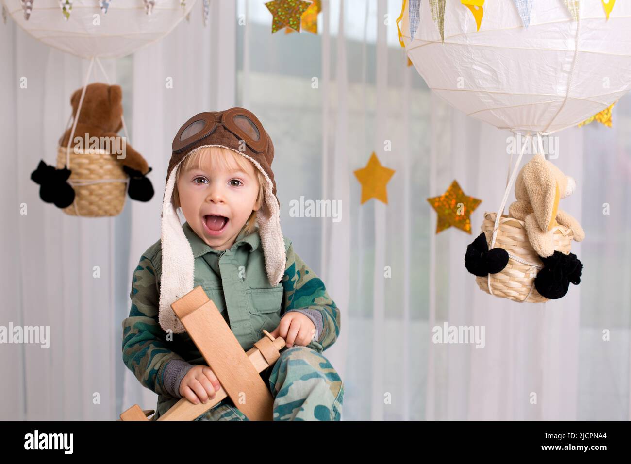 Sweet toddler boy, playing with airplane and teddy bear, decorated air ...