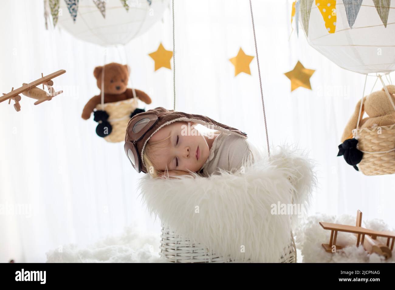 Sweet toddler boy, playing with airplane and teddy bear, decorated air ...