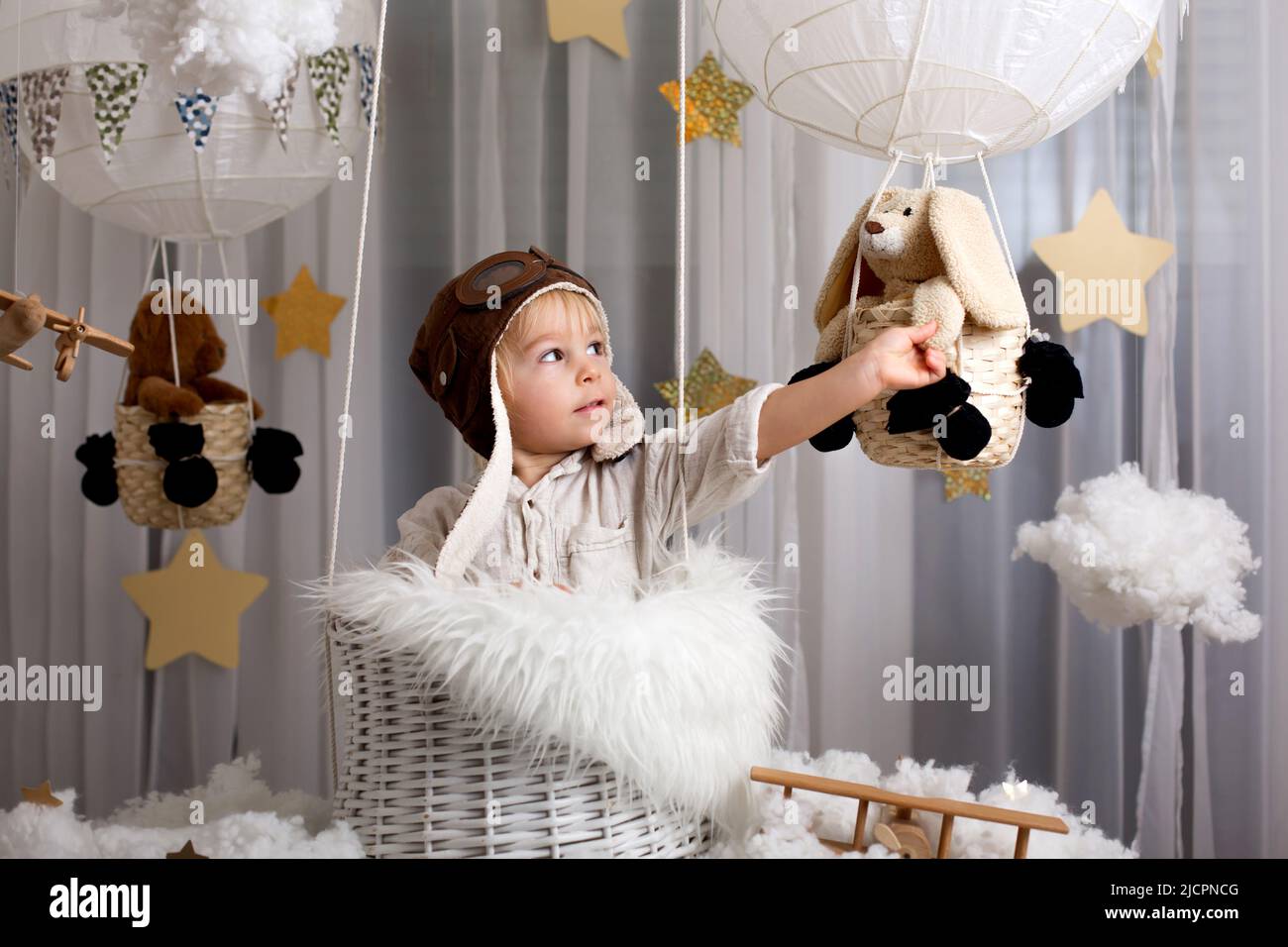 Sweet toddler boy, playing with airplane and teddy bear, decorated air ...