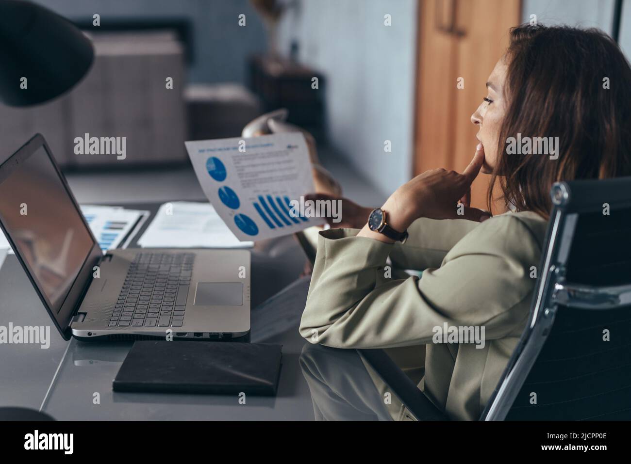Woman sits at her desk reviewing documents Stock Photo - Alamy
