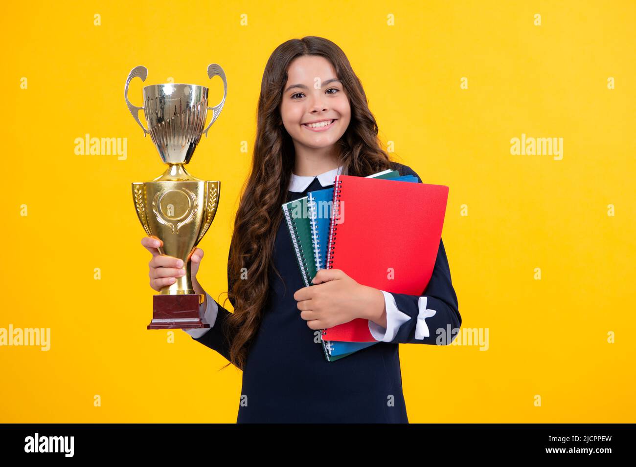 Schoolgirl in school uniform celebrating victory with trophy. Teen ...