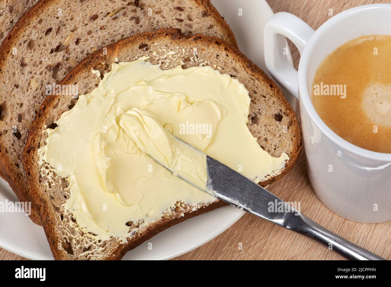 Bread and butter. A knife spreading butter on bread Stock Photo - Alamy