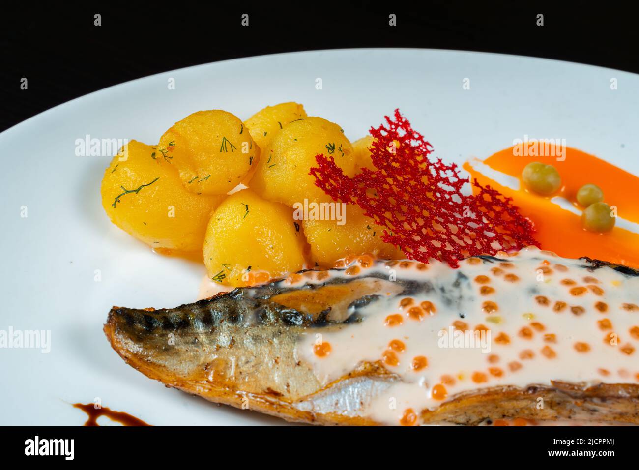 Grilled capelin with potatoes and different sauces on a black ...