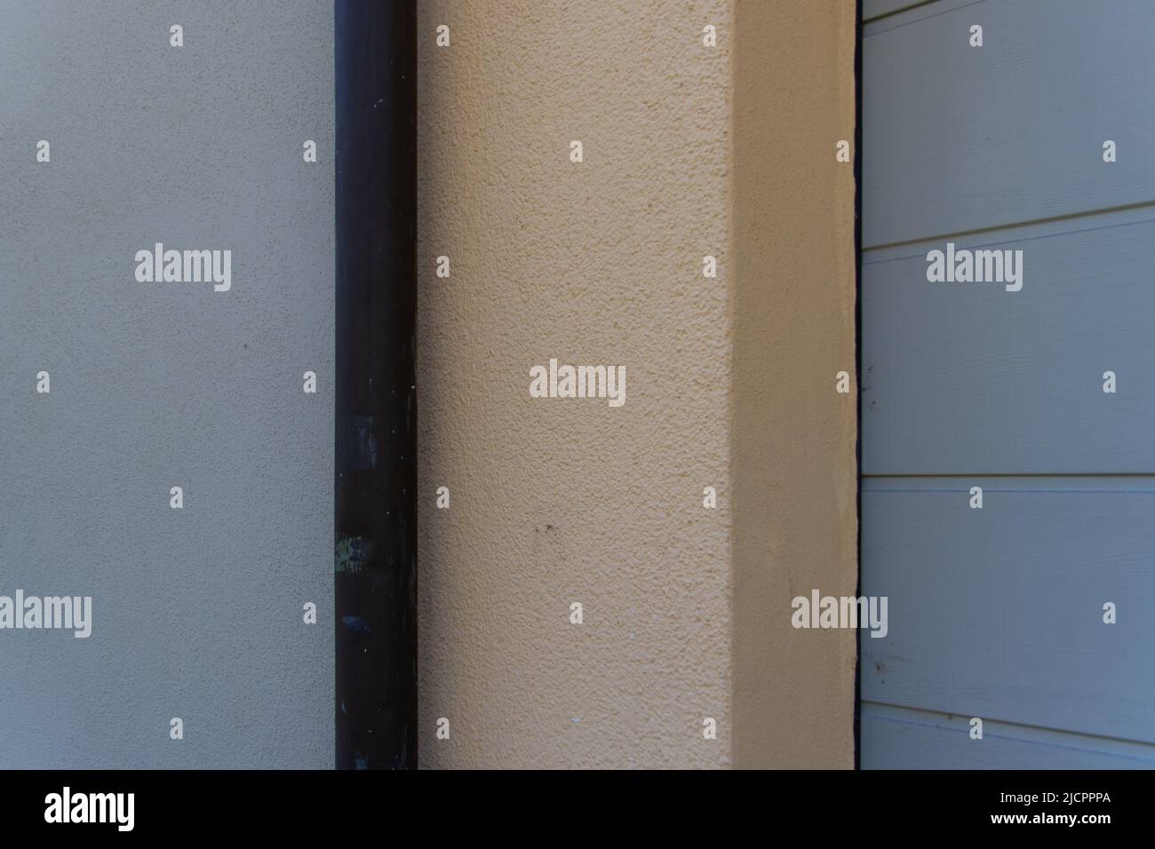 Vertical drain pipe on a grey and beige wall Stock Photo - Alamy