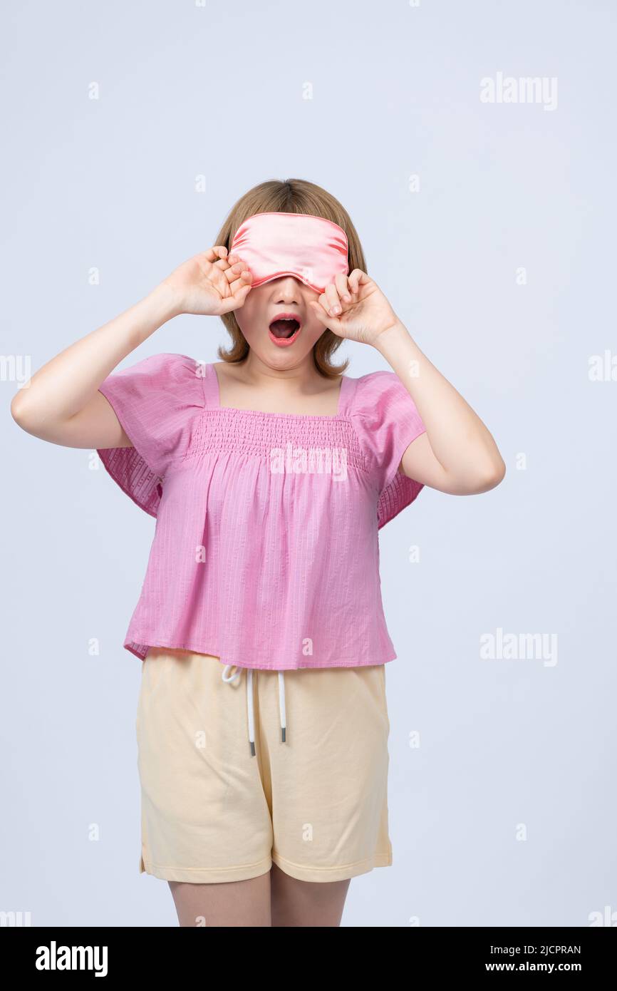 Cheerful asian girl in pajamas standing on white background in sleep ...