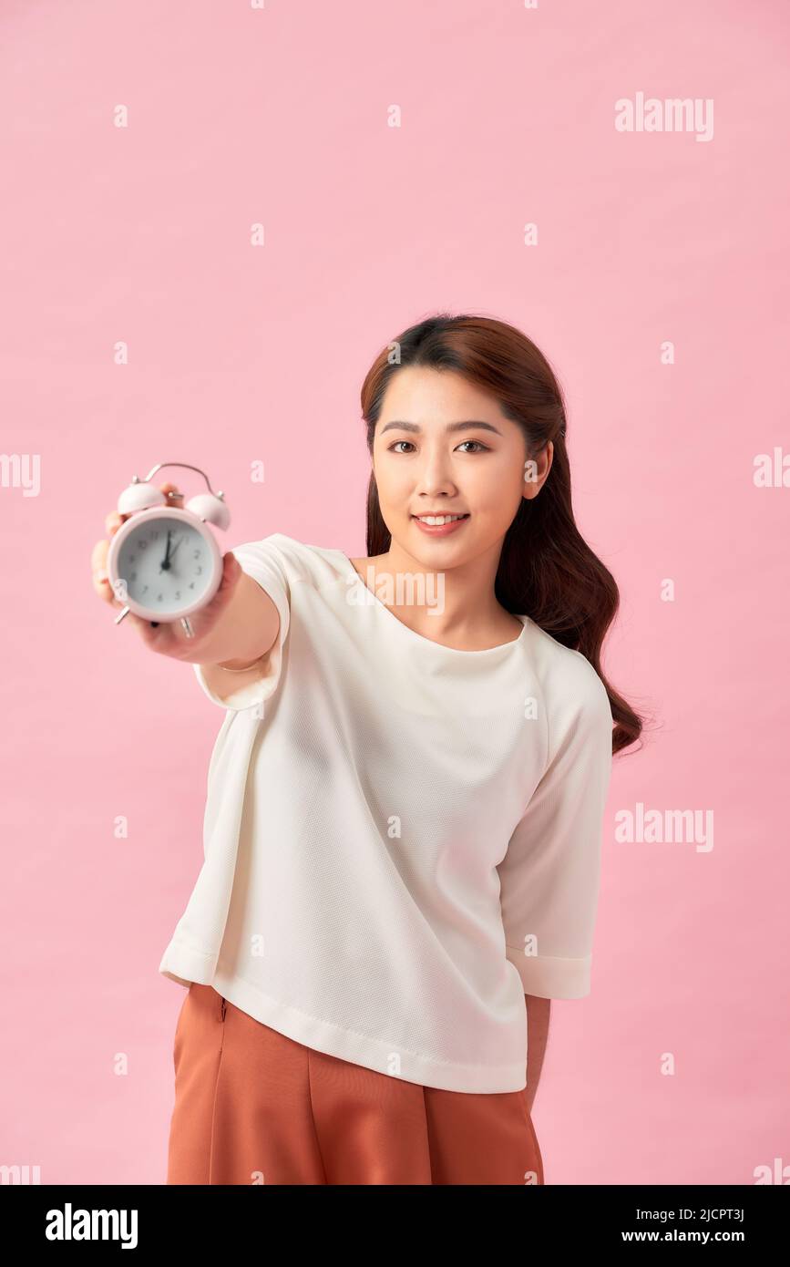 Happy young woman holding white alarm clock and waving hand isolated on ...