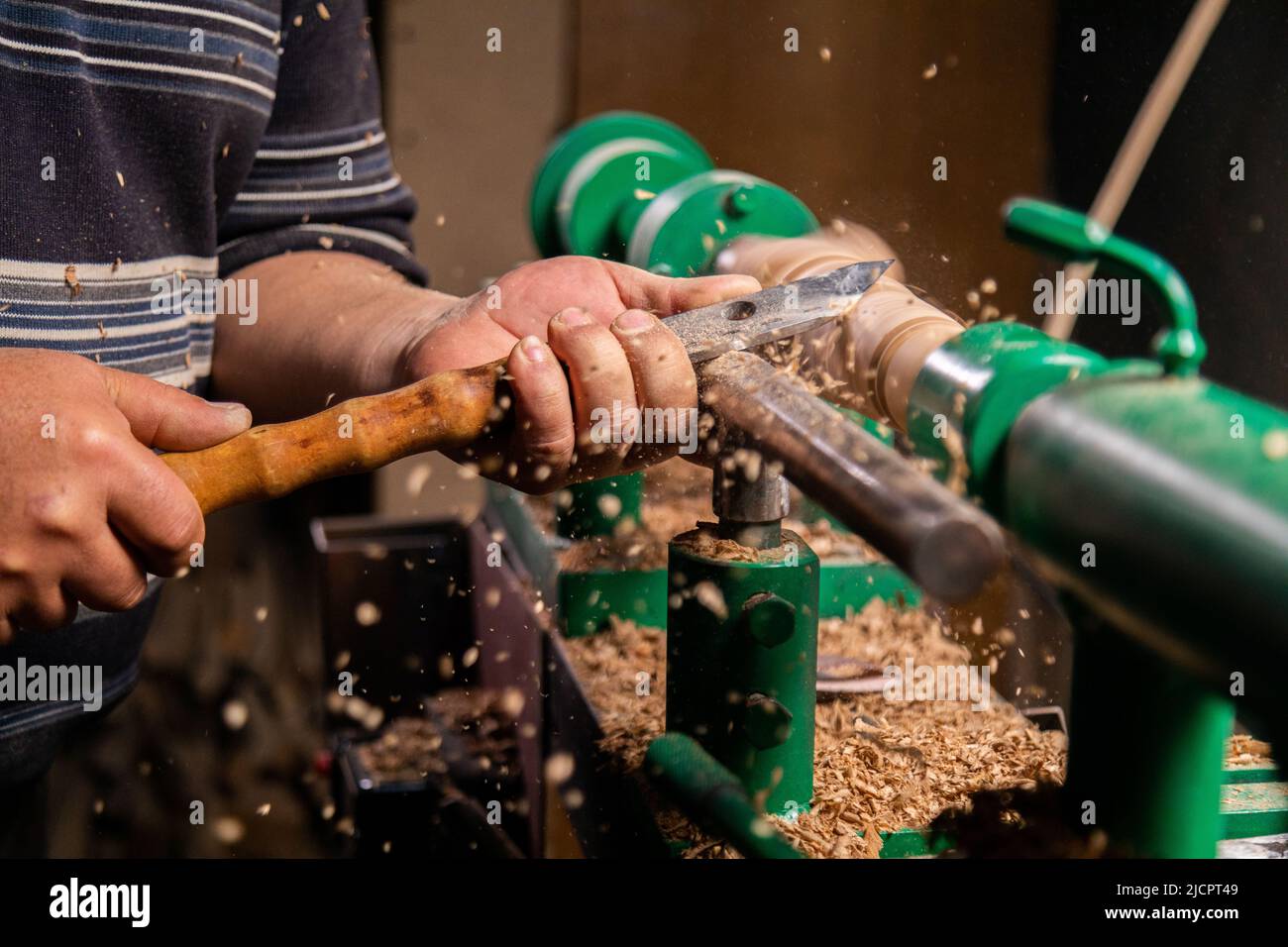 Closeup of carpenter turning wood on a lathe. Person carving chisel ...