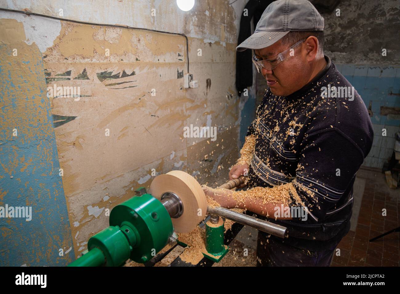 Carpenter turning wood on a lathe. Person carving chisel candlestick on ...