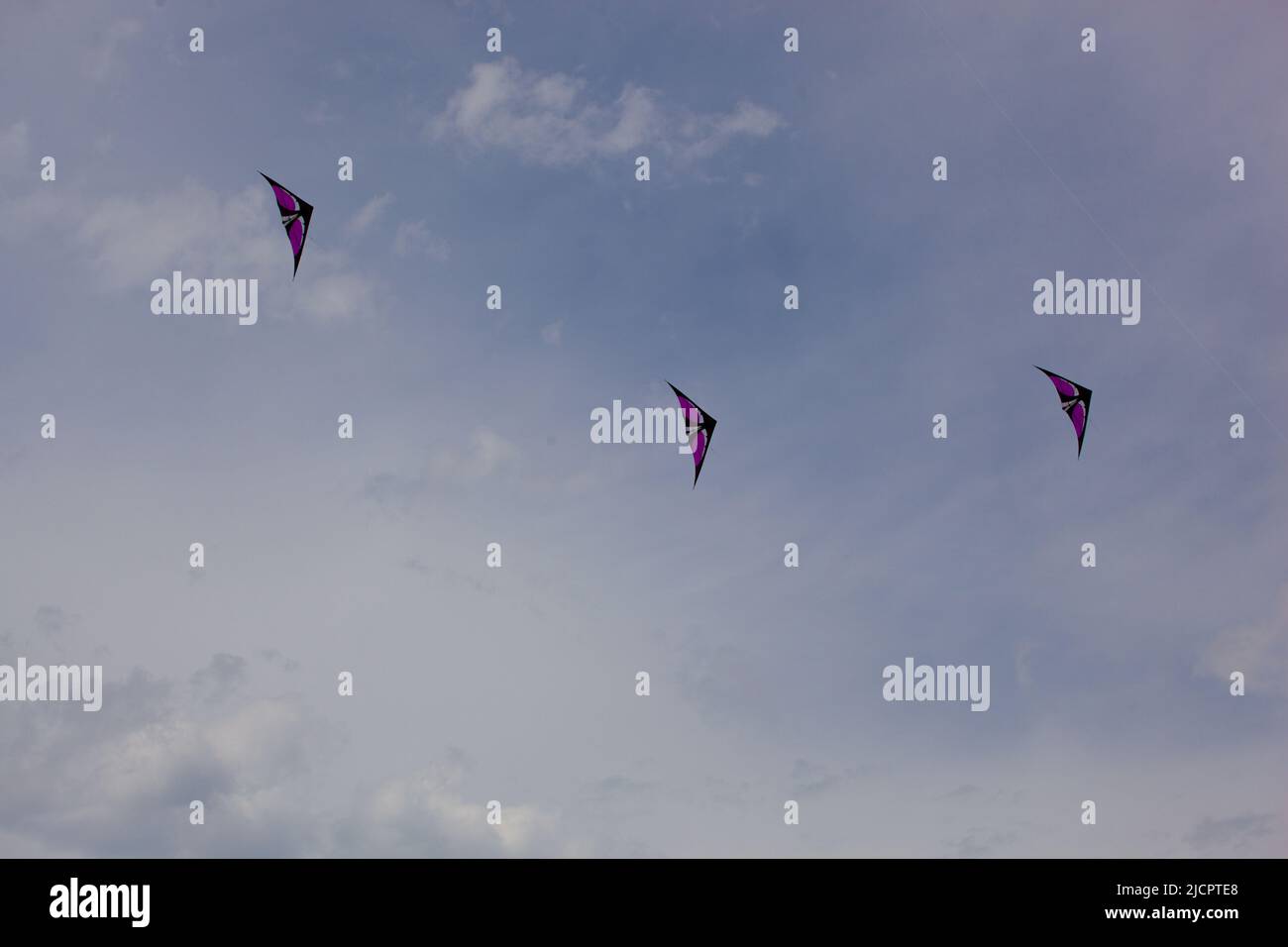 A purple tri kite in the blue sky curves to the right Stock Photo - Alamy