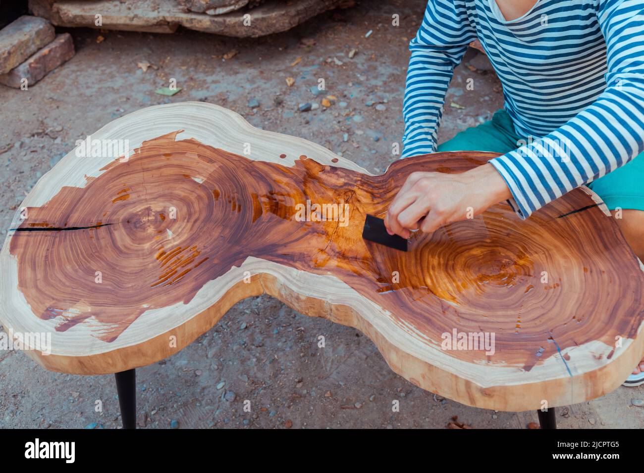 Carpenter pouring linseed oil on a wooden table. Process of making wood ...