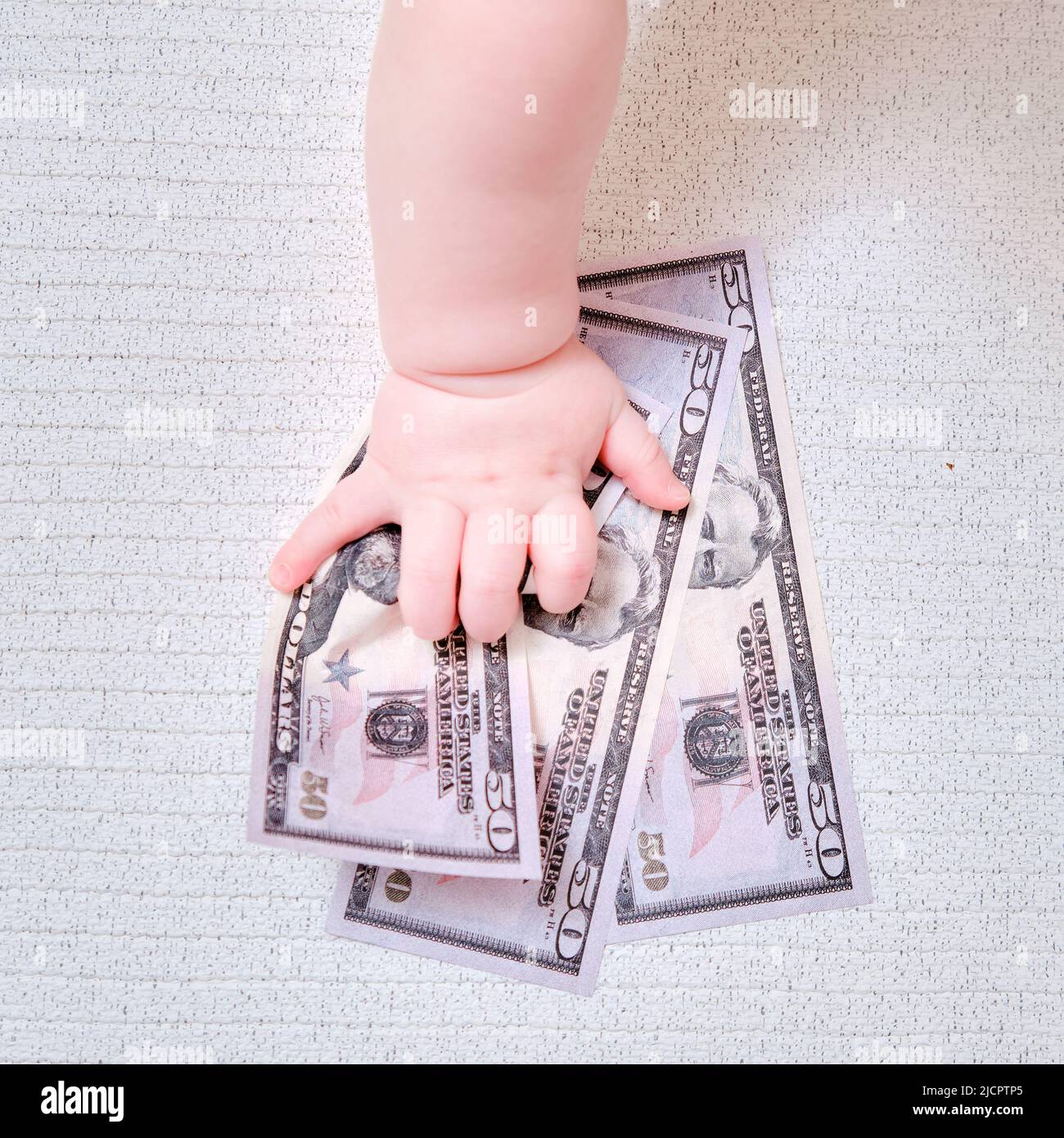 Baby hand and money US dollars, close-up. Children fingers and an ...