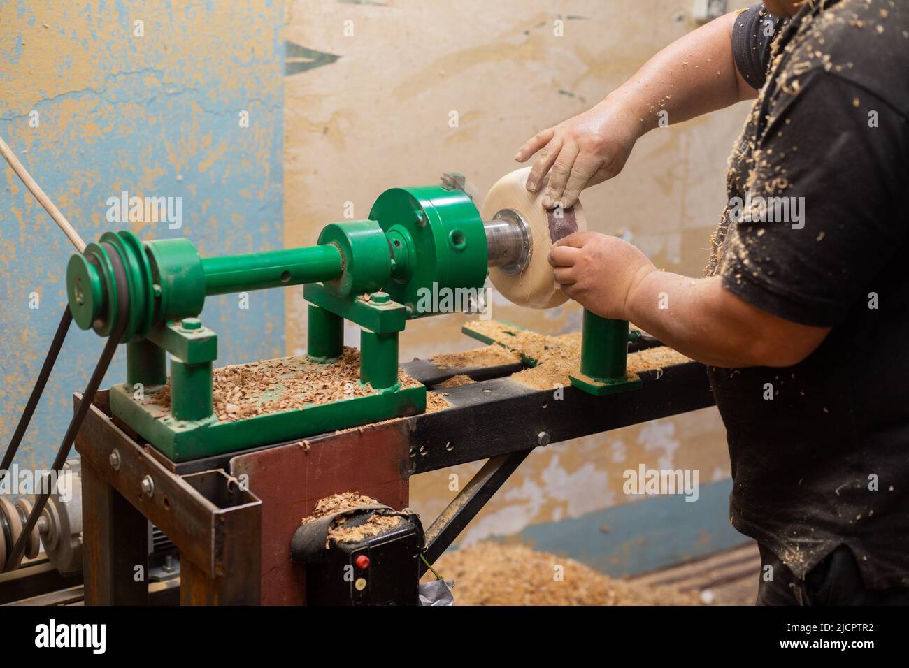 Closeup of person sanding wooden product using sandpaper on a lathe ...