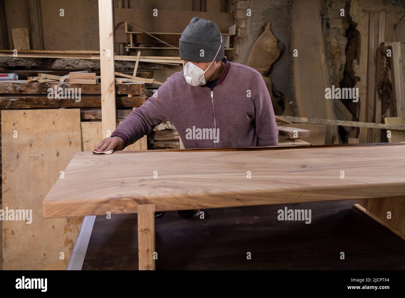 Carpenter coating a wooden table with protective flaxseed oil. Process ...