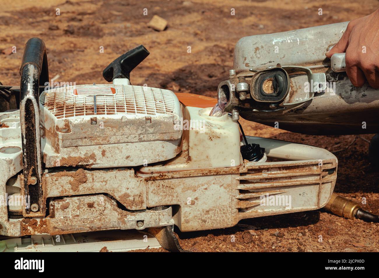 Closeup of lumberjack pouring gas to oil mixture into the chainsaw fuel ...