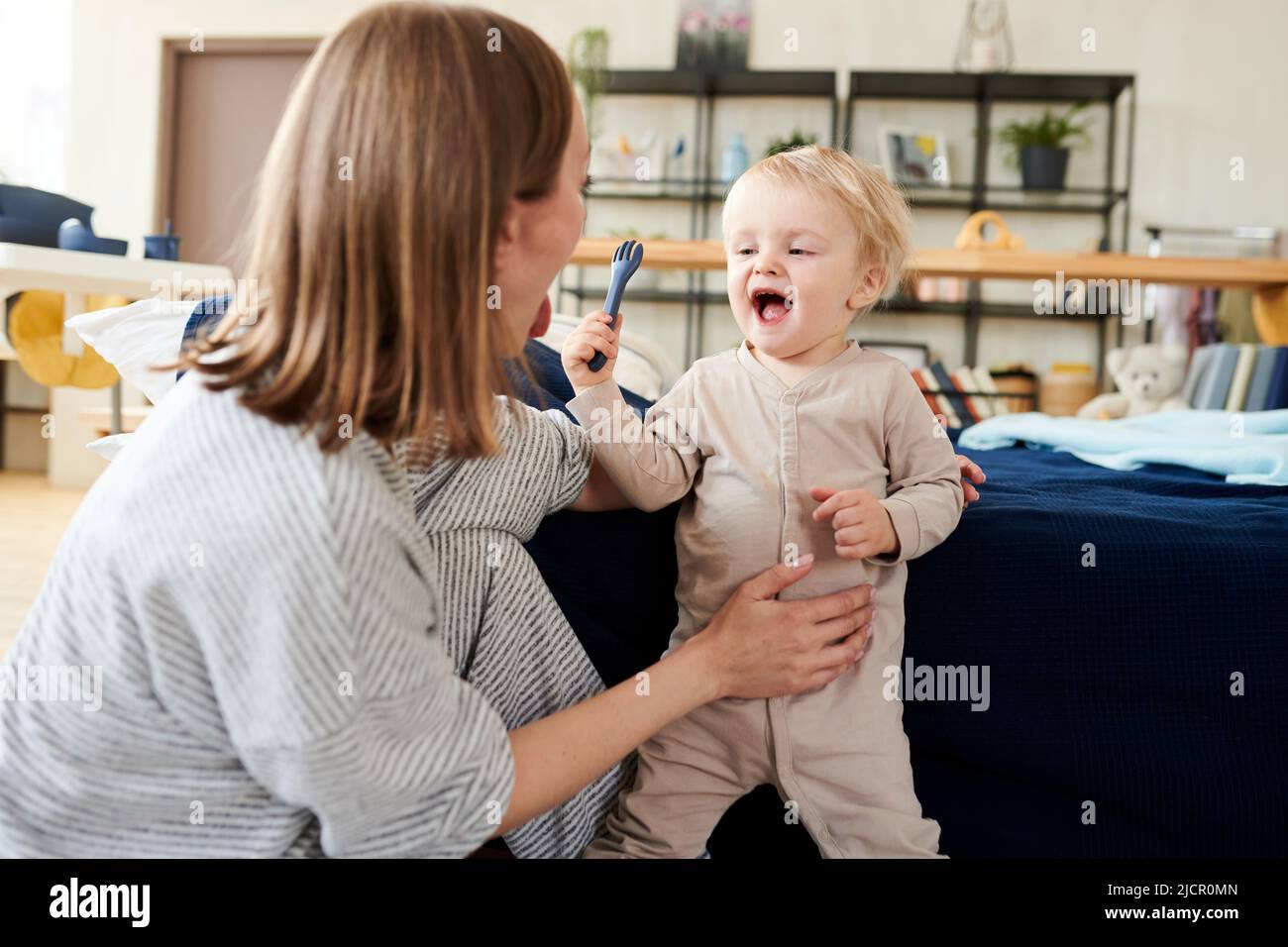 Happy child having fun on sofa together with his mother during leisure ...
