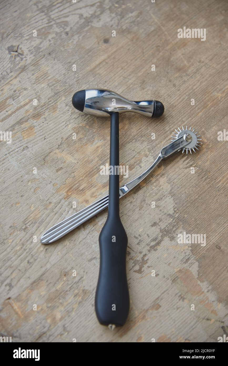 A medical reflex hammer and a Wartenberg wheel lie on a gray wooden surface Stock Photo - Alamy