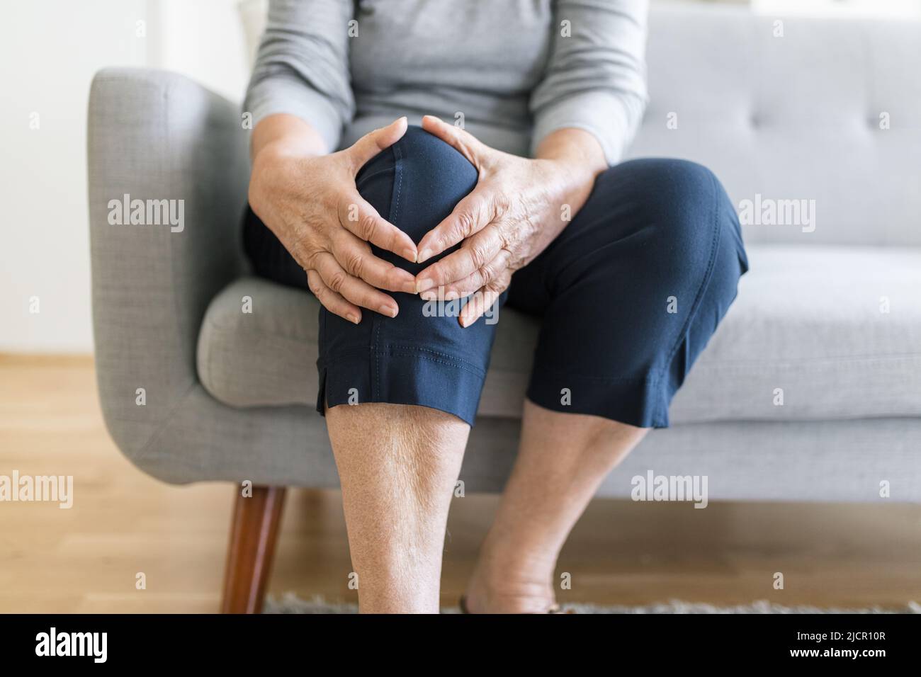 Senior woman sitting on bench, holding her painful knee Stock Photo - Alamy
