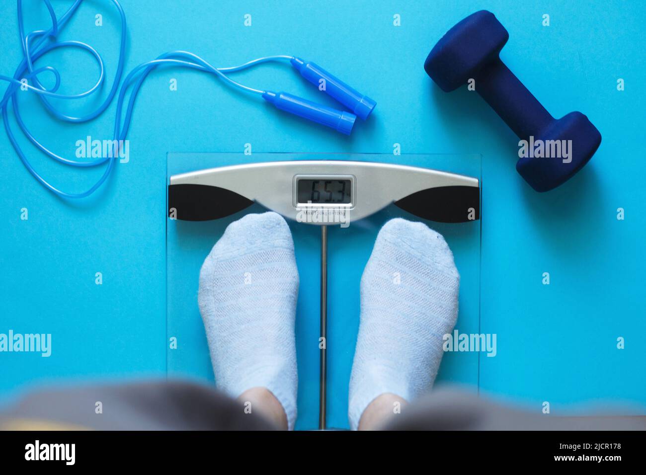 Woman measures her weight by standing her feet in socks on scale on a ...