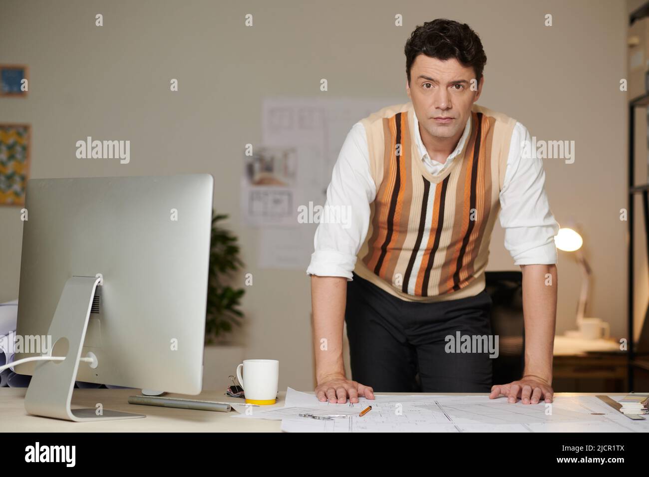 Portrait of determined professional architect leaning on table with ...